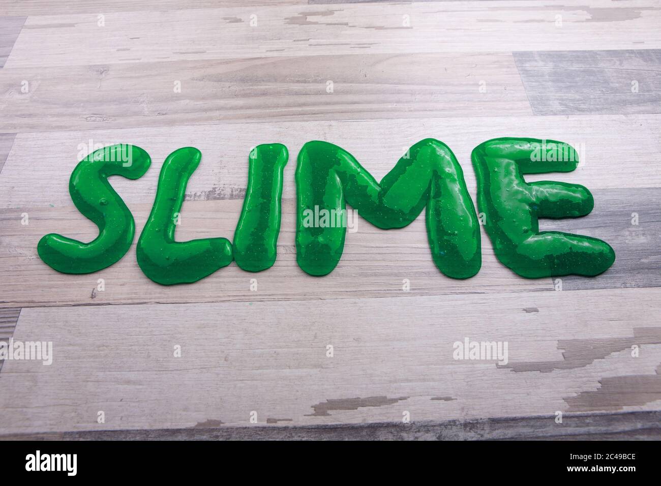 Slime text made from green slimeon a wooden table surface Stock Photo ...