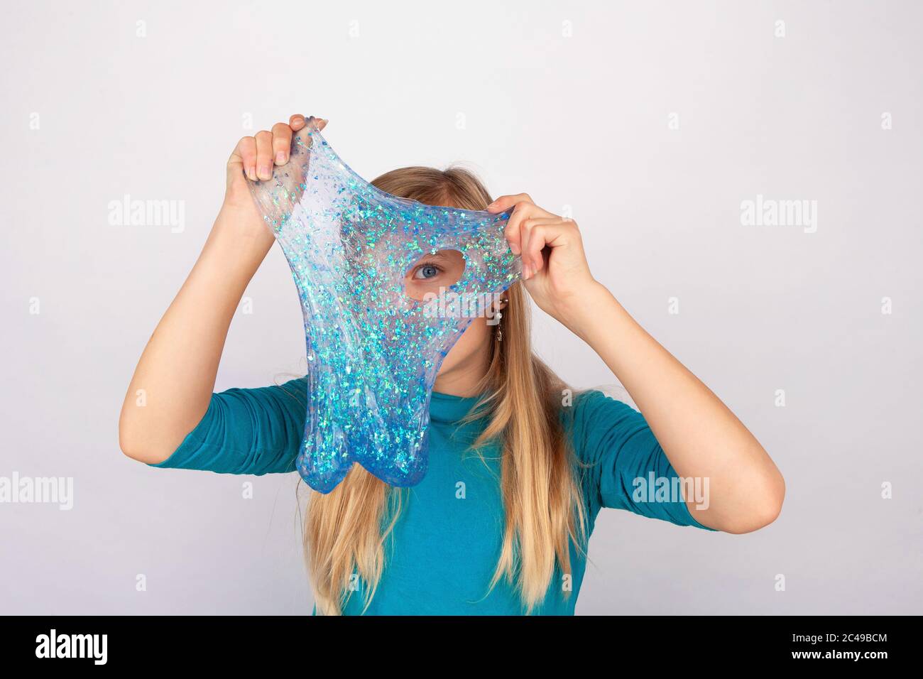 Cute girl holdin a slime in front of her face and looking through its ...