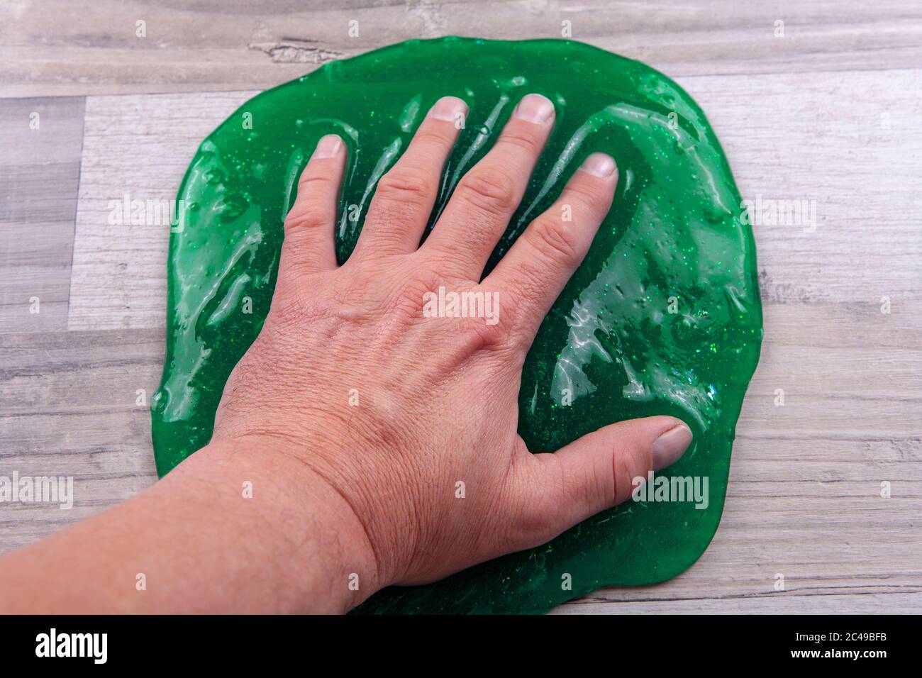 Hand squeezing a slime toy on a table Stock Photo - Alamy