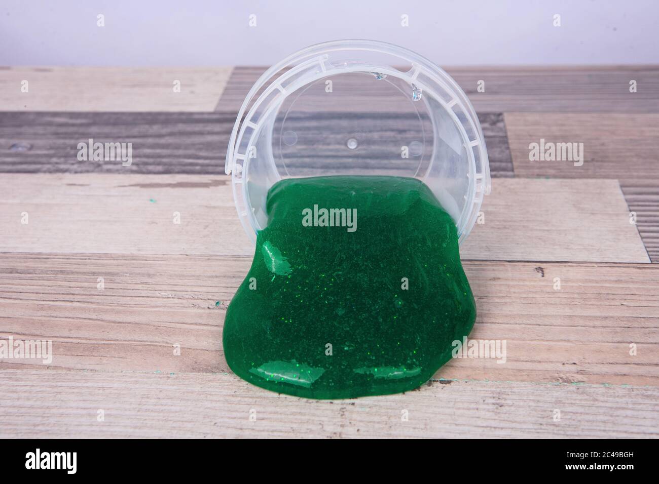 Green slime flowing out of a plastic bucket on a wooden table Stock ...
