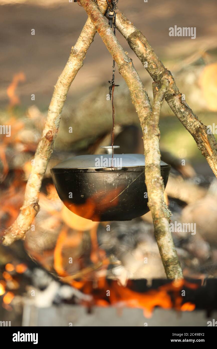 Cooking meat outdoors in a cast-iron pot. Summer outdoor activities ...