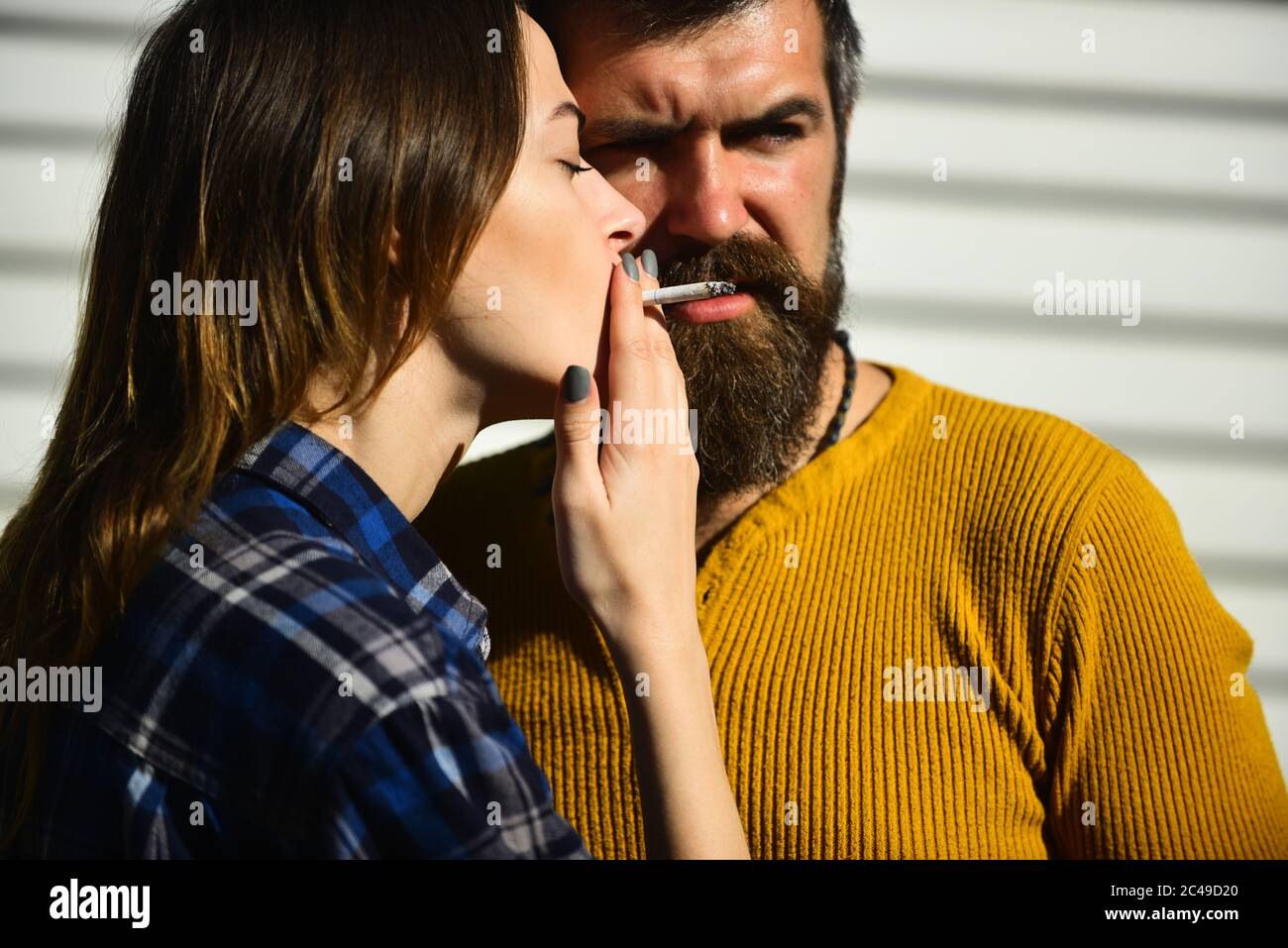 Couple in love smokes together. Girl and bearded guy hold cigarette ...