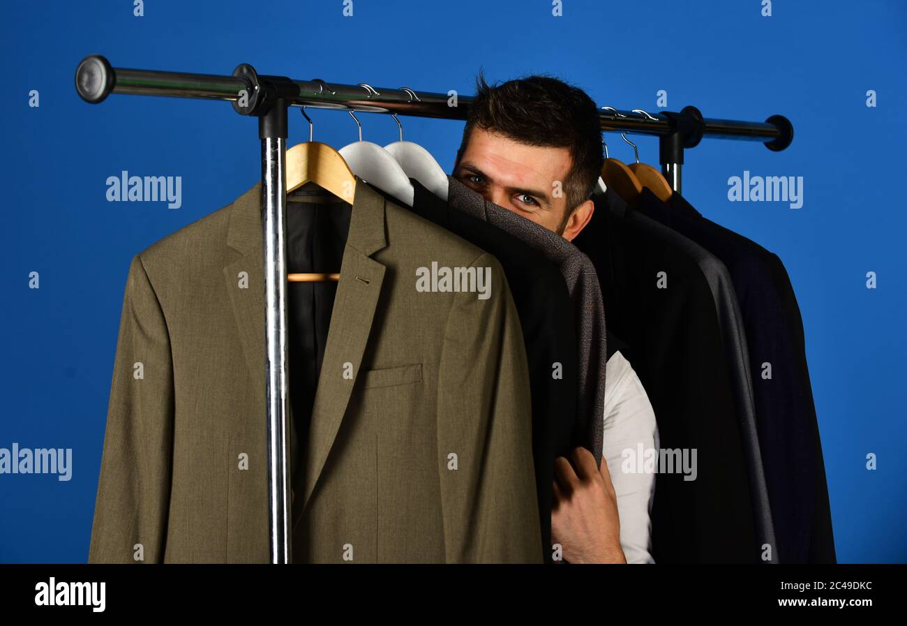 Designer hides among suits on clothes hangers. Fashion choice concept ...