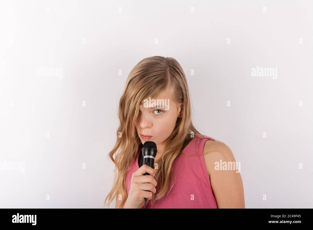 Young cute girl holding a microphone singing karaoke Stock Photo - Alamy