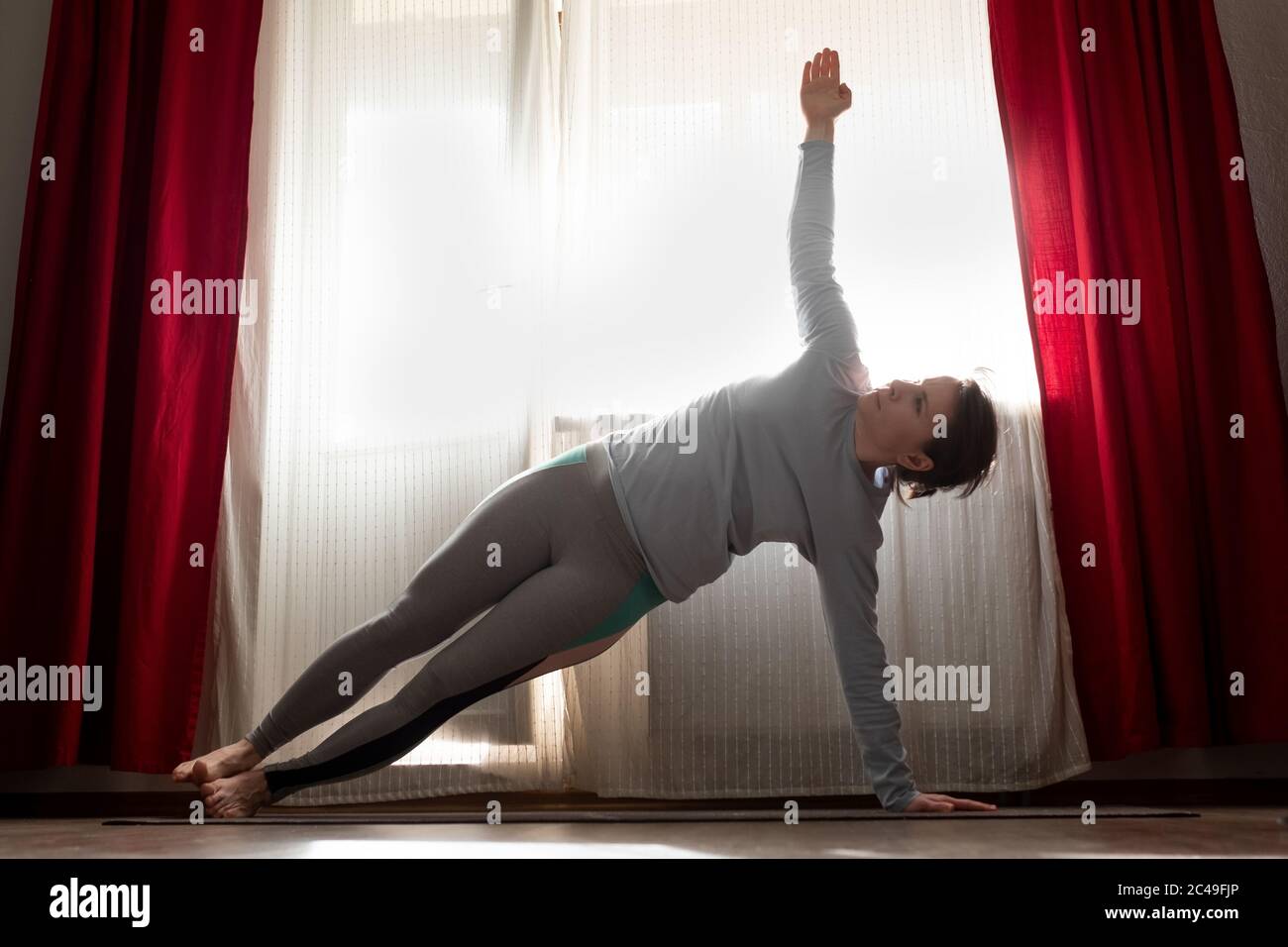 young woman doing side plank pose at home Stock Photo - Alamy
