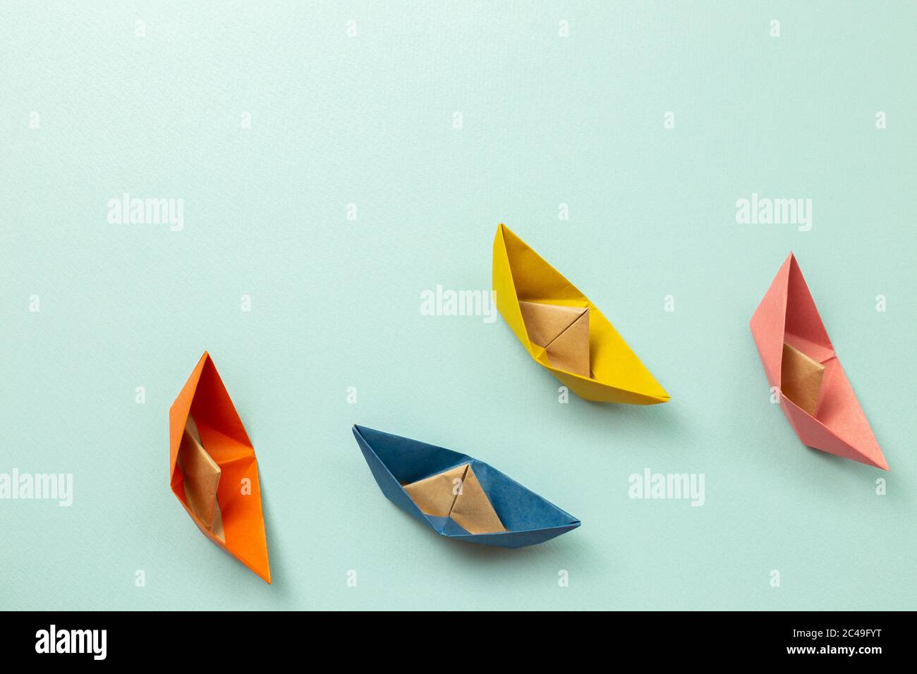 Colorful paper ships on blue background. ships heading for the same ...