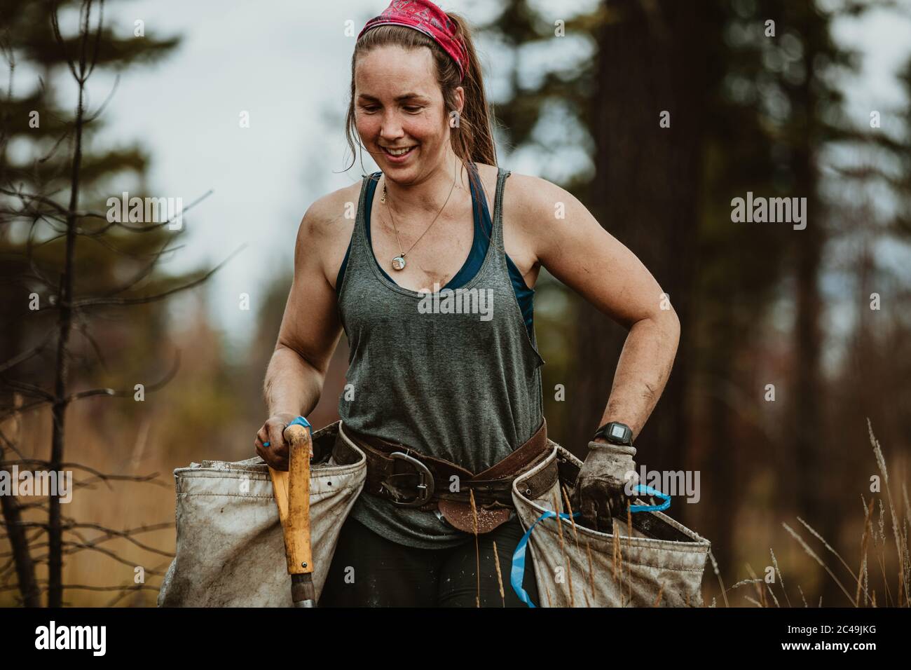 Woman planting trees in forest. Female tree planter carrying bags full ...