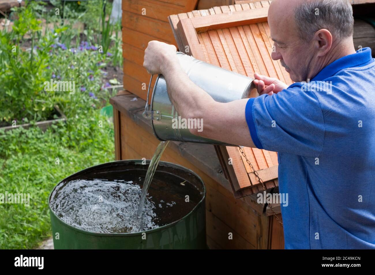 Man draw water from the well to water flowers in garden Stock Photo - Alamy
