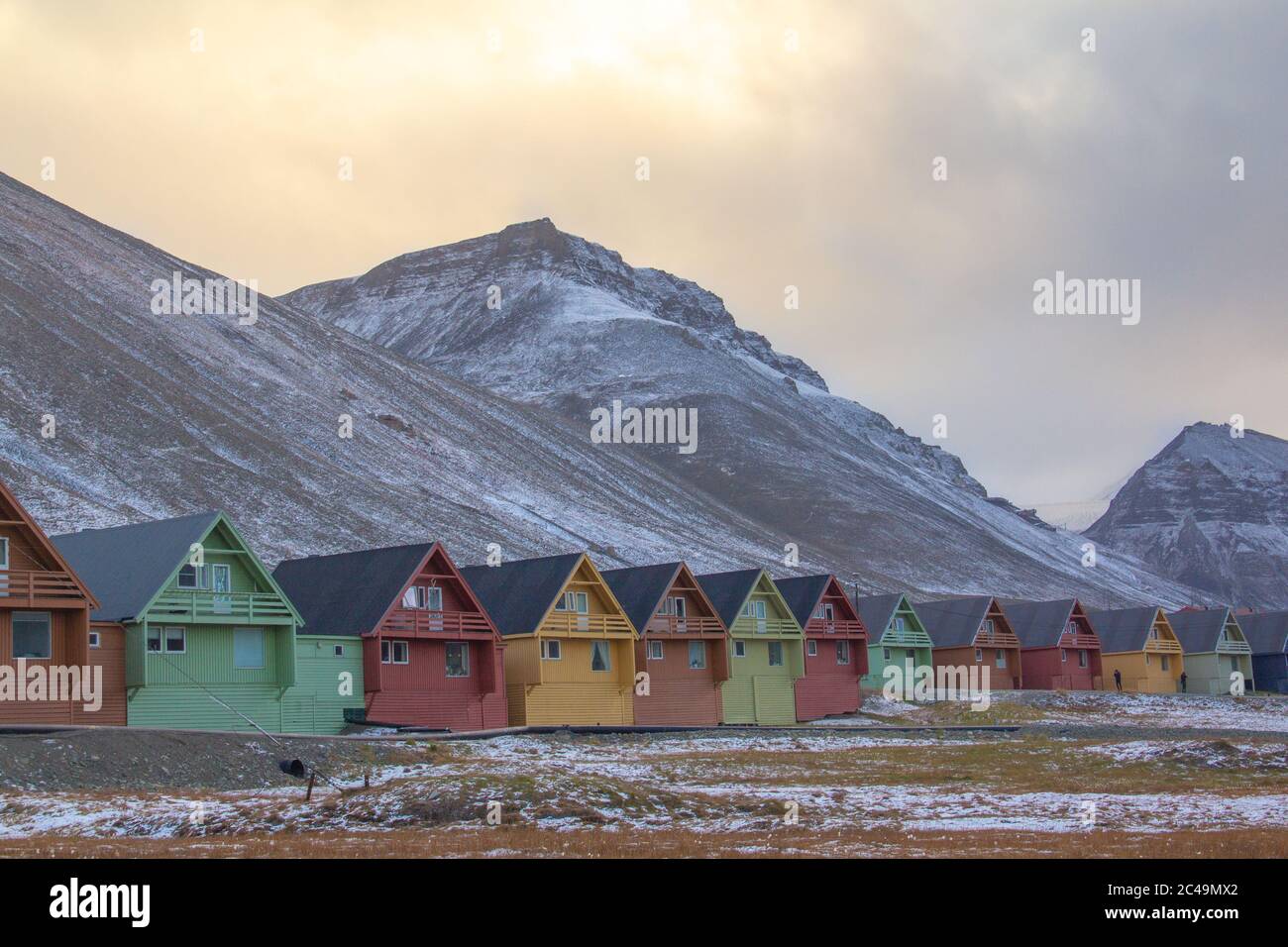 Shot of colorful houses surrounded by giant mountains covered in snow ...