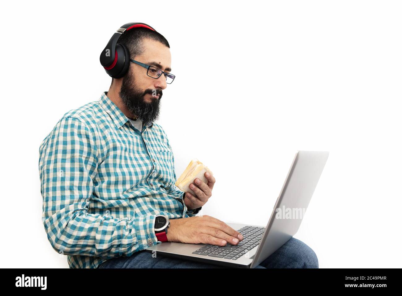man isolated on white background typing on a laptop while eating a ...