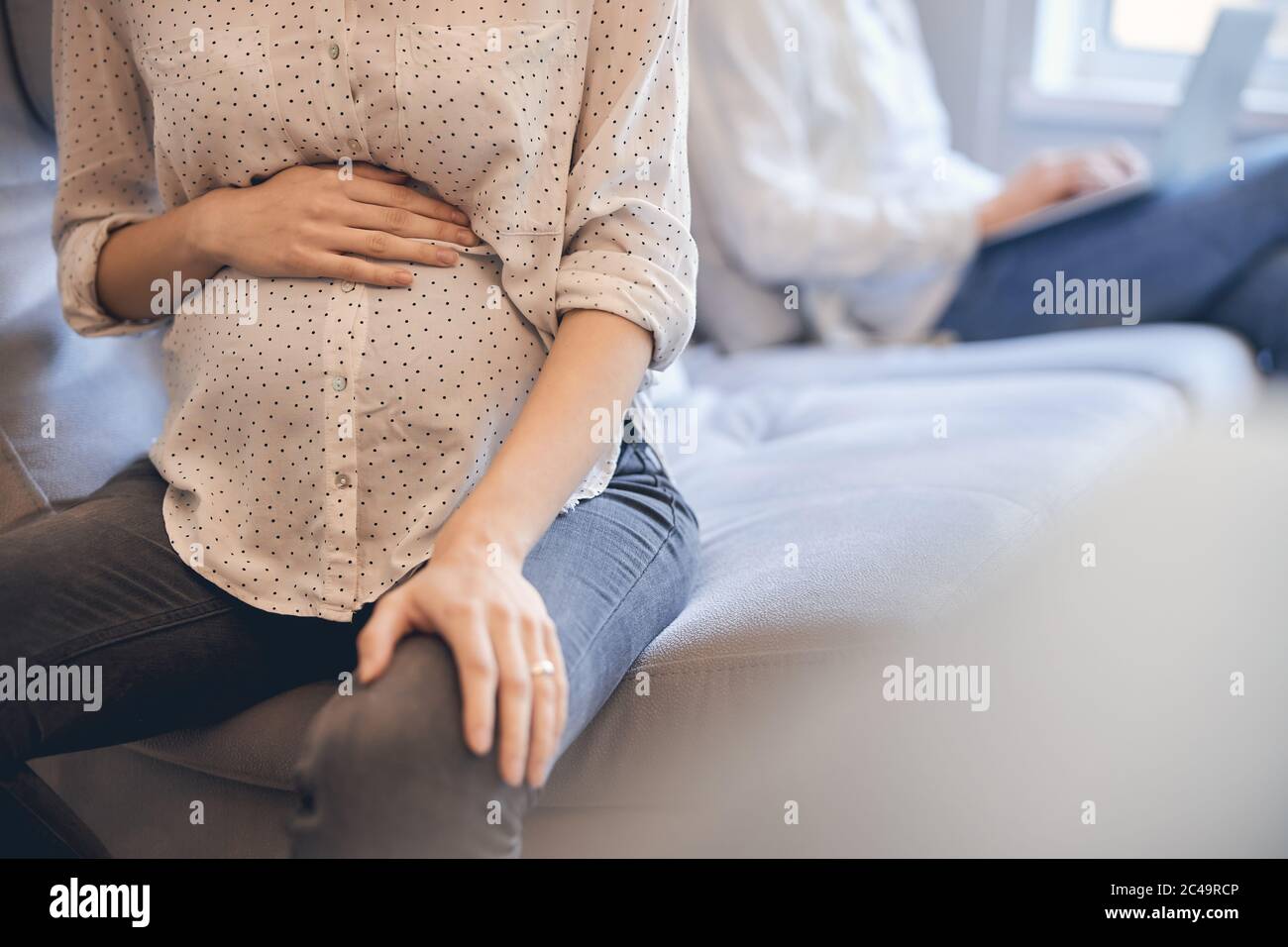 Woman in shirt and jeans touching her pregnant belly Stock Photo - Alamy