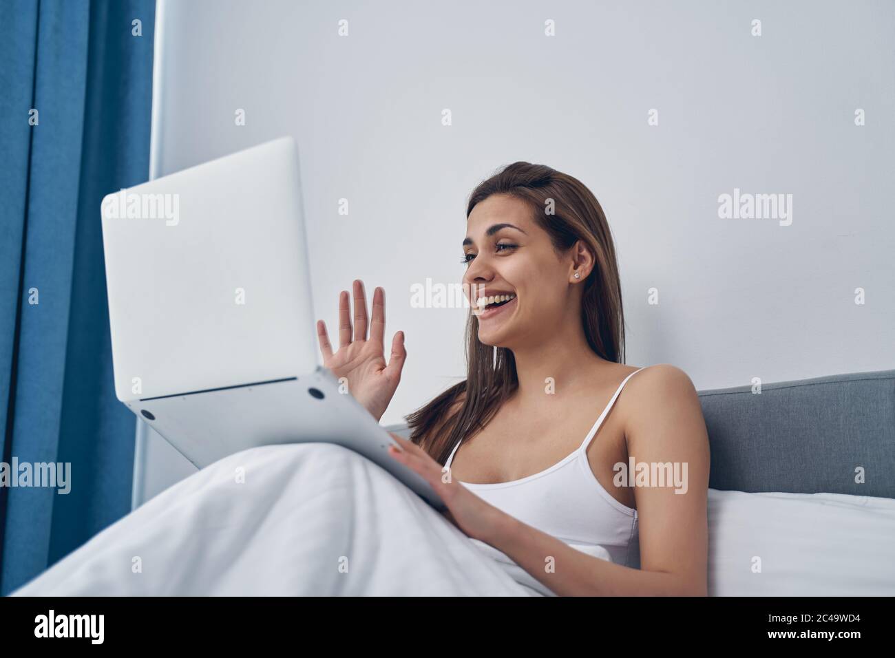Cheerful young woman chatting with friend through video call Stock ...