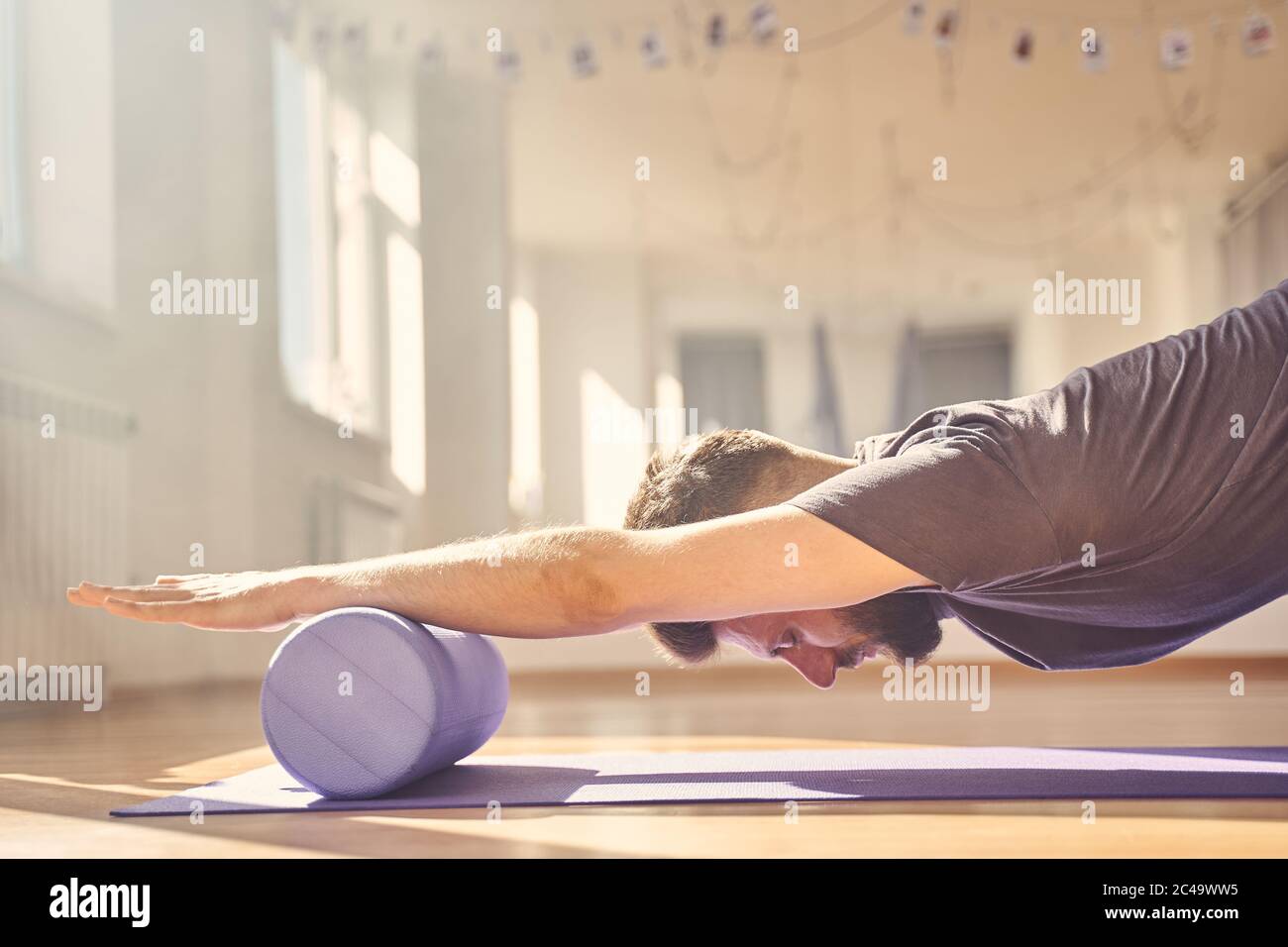 Young man doing exercise with yoga foam roller Stock Photo - Alamy