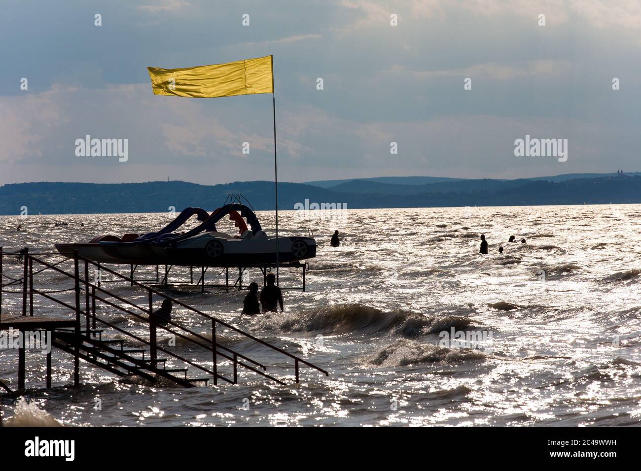 Lake Balaton beach in backlight with silhouettes of bathers and paddle ...
