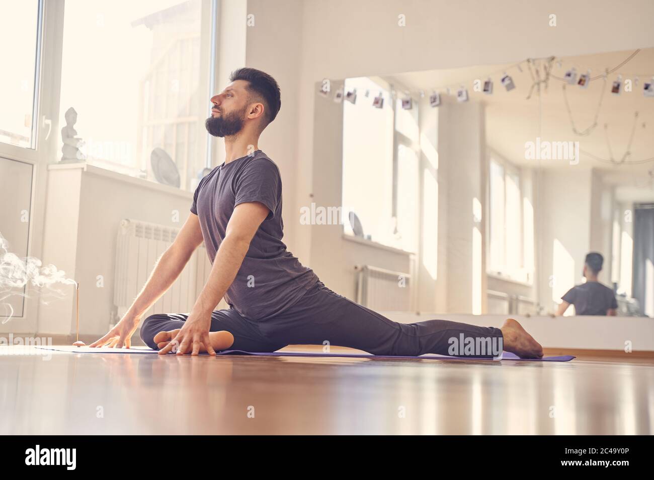 Handsome young man doing seated pigeon yoga pose Stock Photo - Alamy