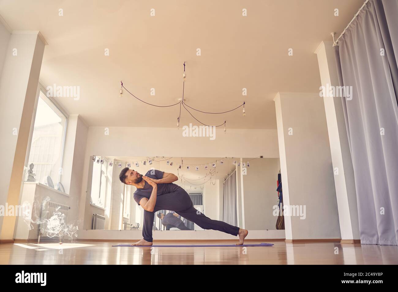 Male yoga practitioner doing prayer twist pose Stock Photo - Alamy