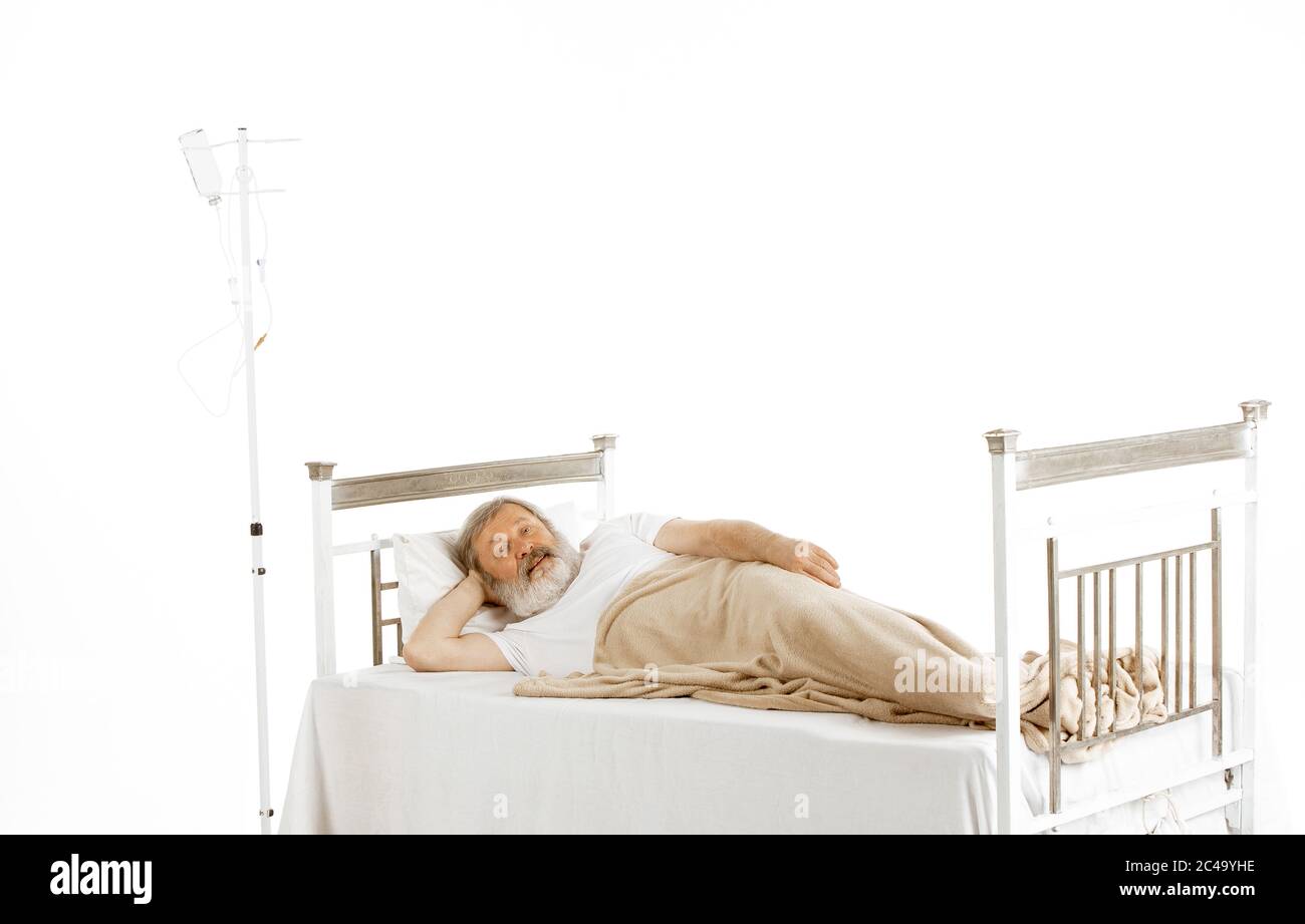 Elderly old man recovering in a comfortable hospital bed isolated on ...