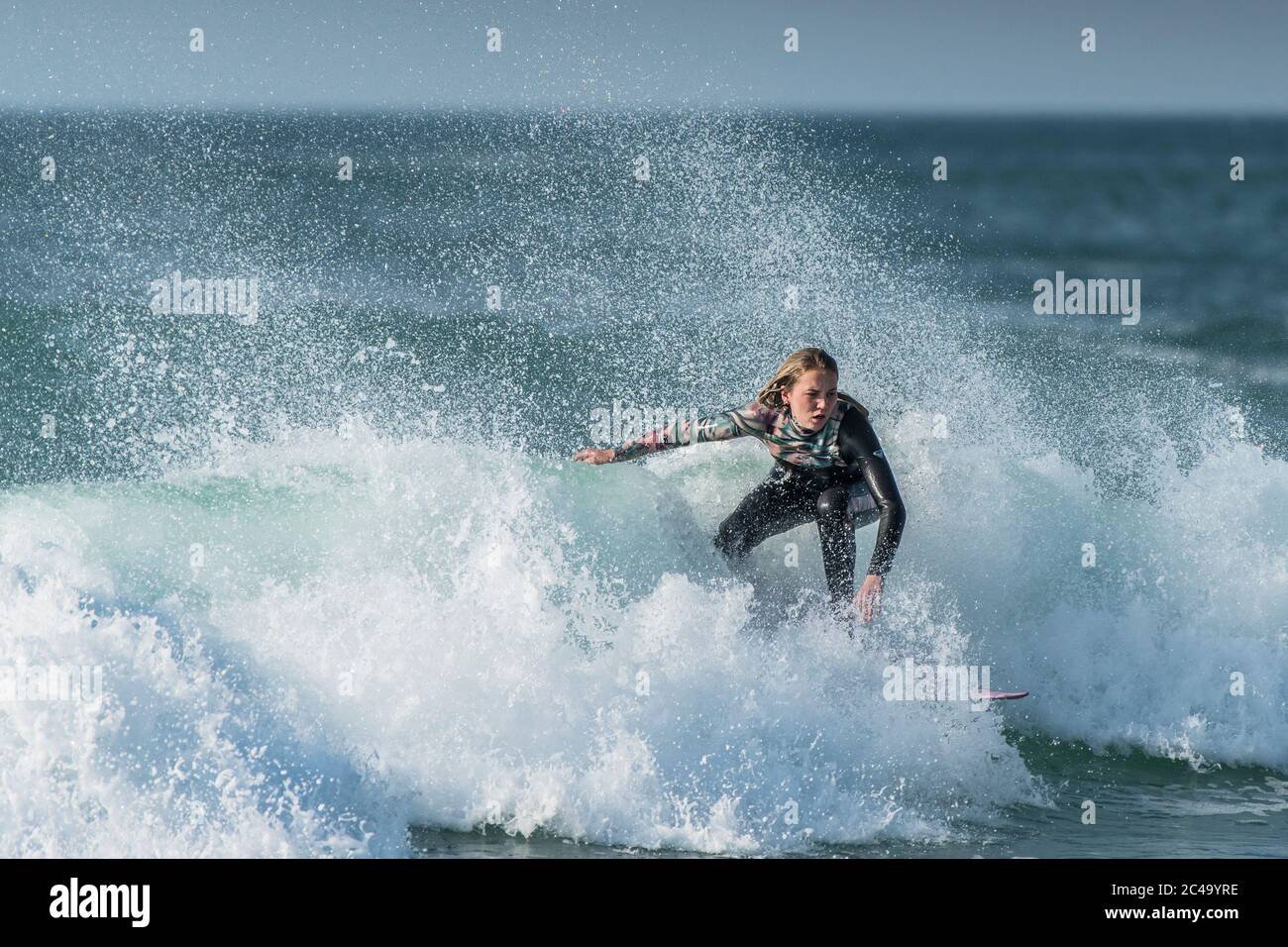 A teenage female surfer surfing at Fistral in Newquay in Cornwall Stock ...