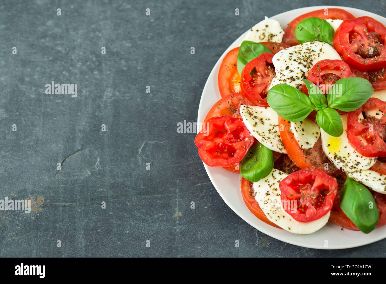 Fresh caprese salad with mozzarella, tomato, basil and spices on the ...