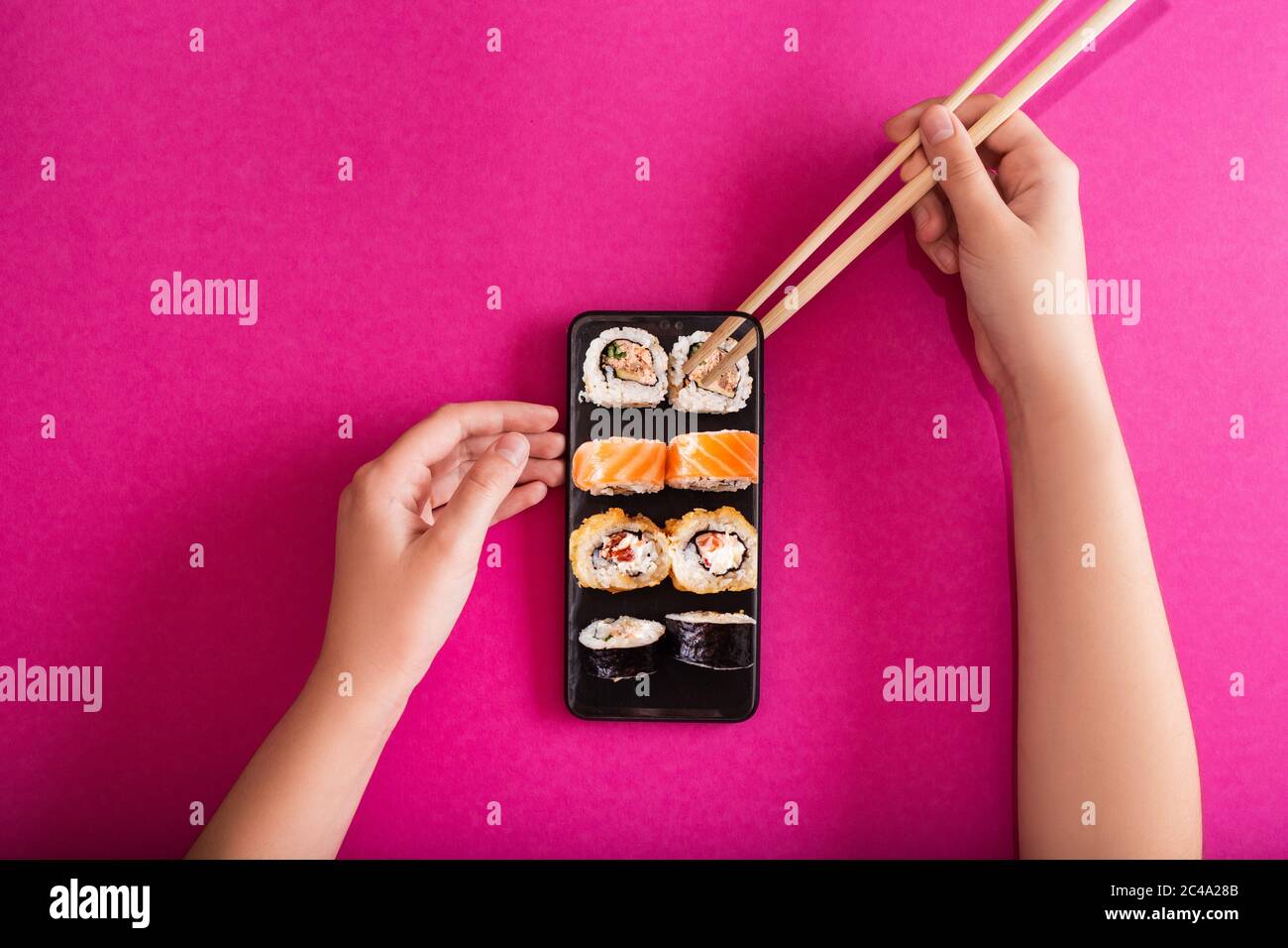 Female hand holding chopsticks and mobile phone with tasty sushi roll ...