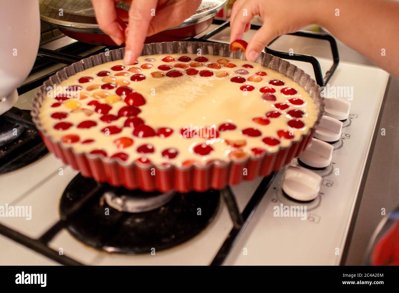 young boy is cooking and baking cherry pie with almond slices with his ...