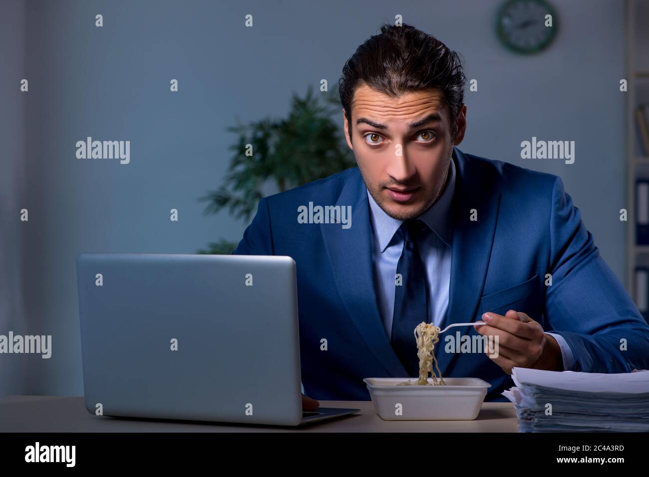 Hungry employee working late in office Stock Photo - Alamy