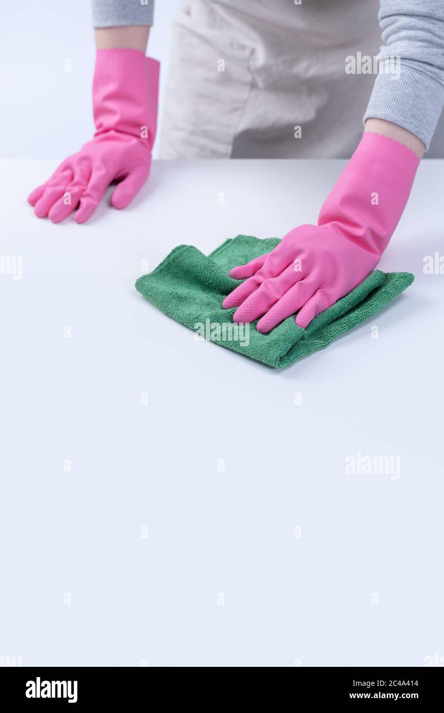 Young woman housekeeper in apron is wearing pink gloves to clean the ...