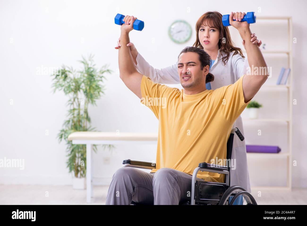Young male patient in wheel-chair doing physical exercises in hospital ...