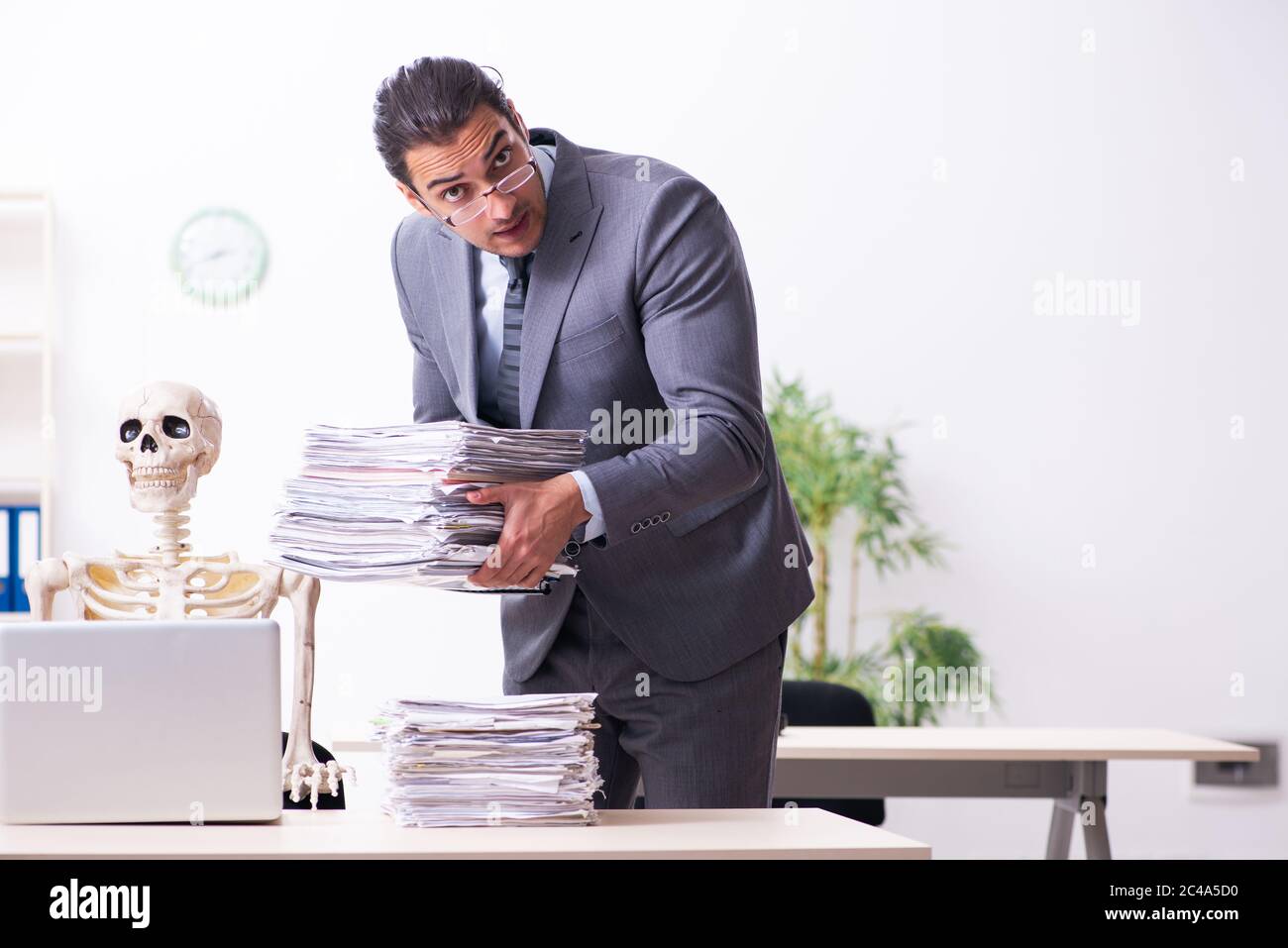 Young employee and skeleton in the office Stock Photo - Alamy