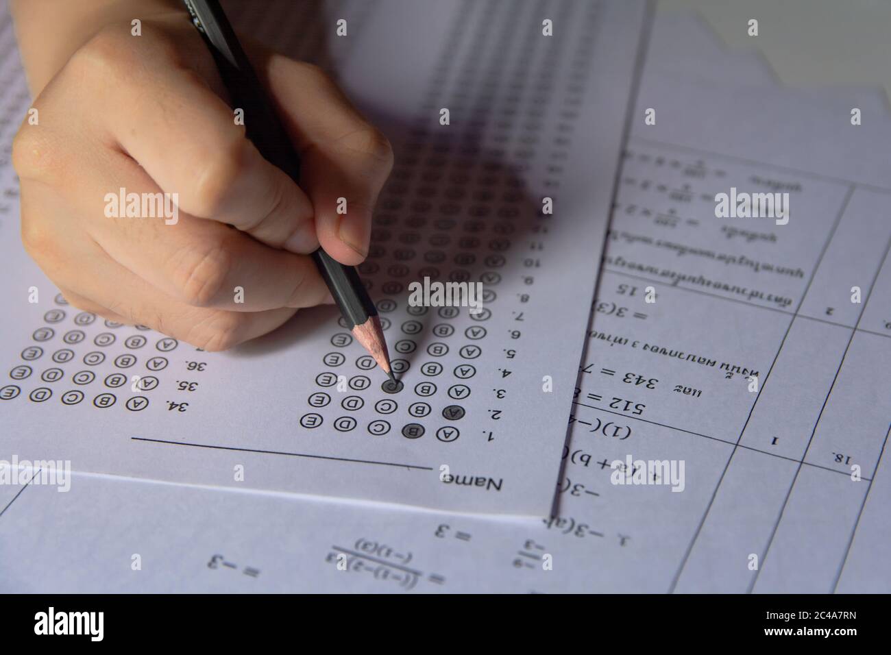Students hand holding pencil writing selected choice on answer sheets ...
