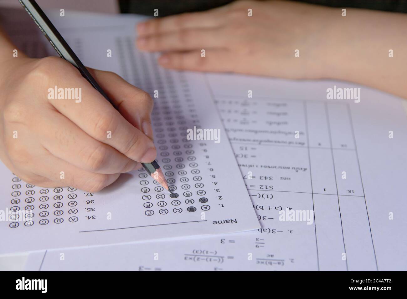 Students hand holding pencil writing selected choice on answer sheets ...