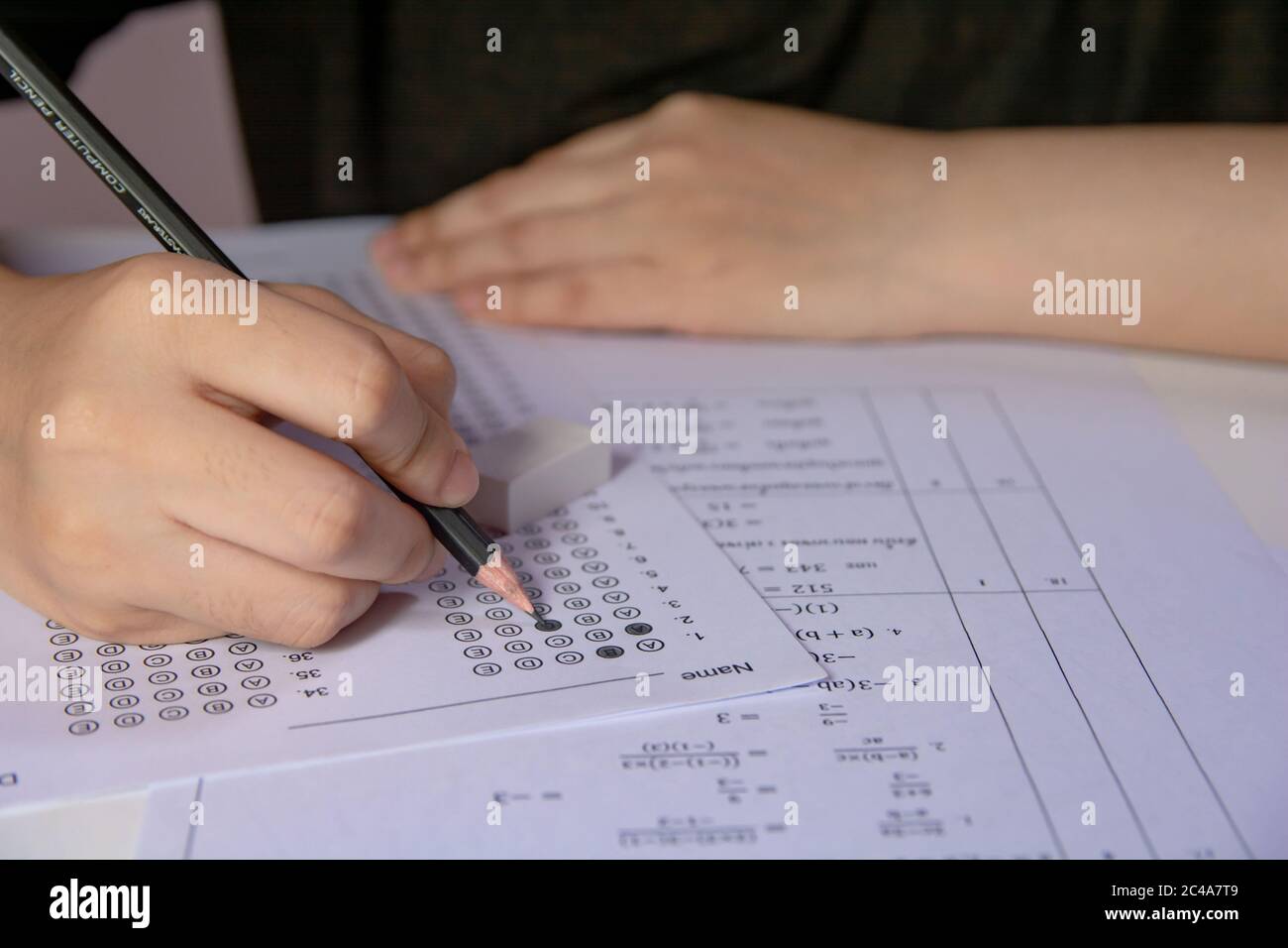 Students hand holding pencil writing selected choice on answer sheets ...
