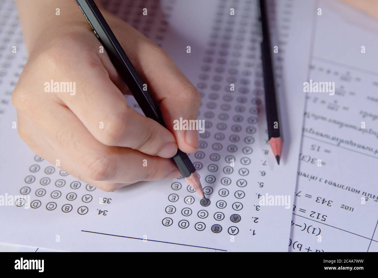 Students hand holding pencil writing selected choice on answer sheets ...
