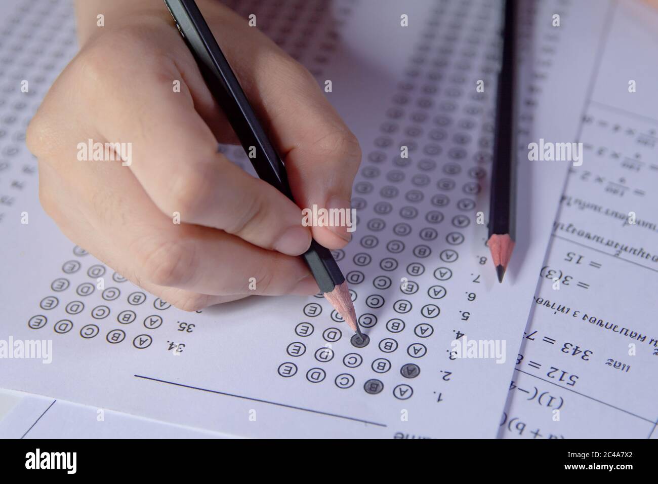 Students hand holding pencil writing selected choice on answer sheets ...