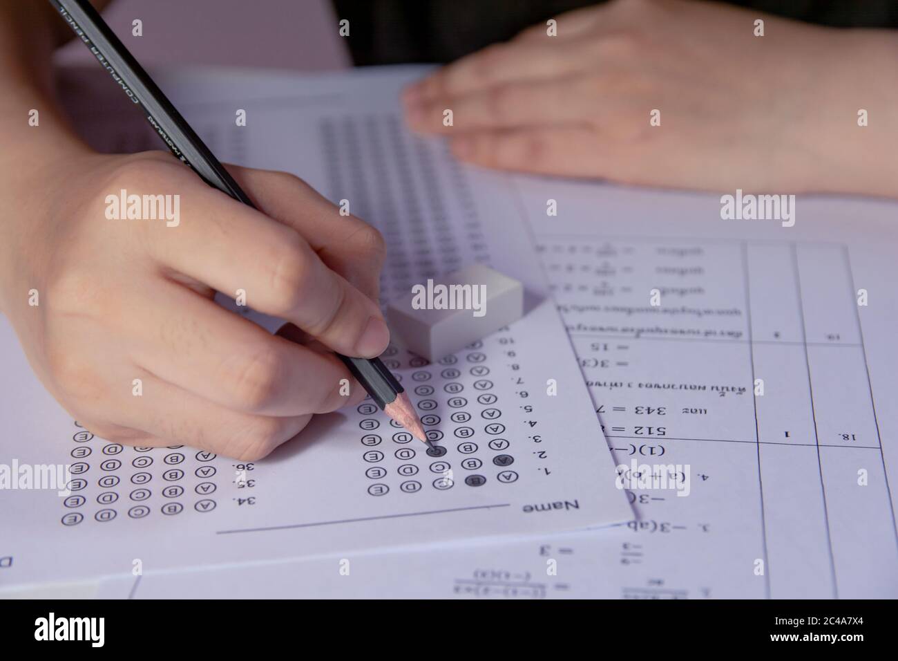 Students hand holding pencil writing selected choice on answer sheets ...