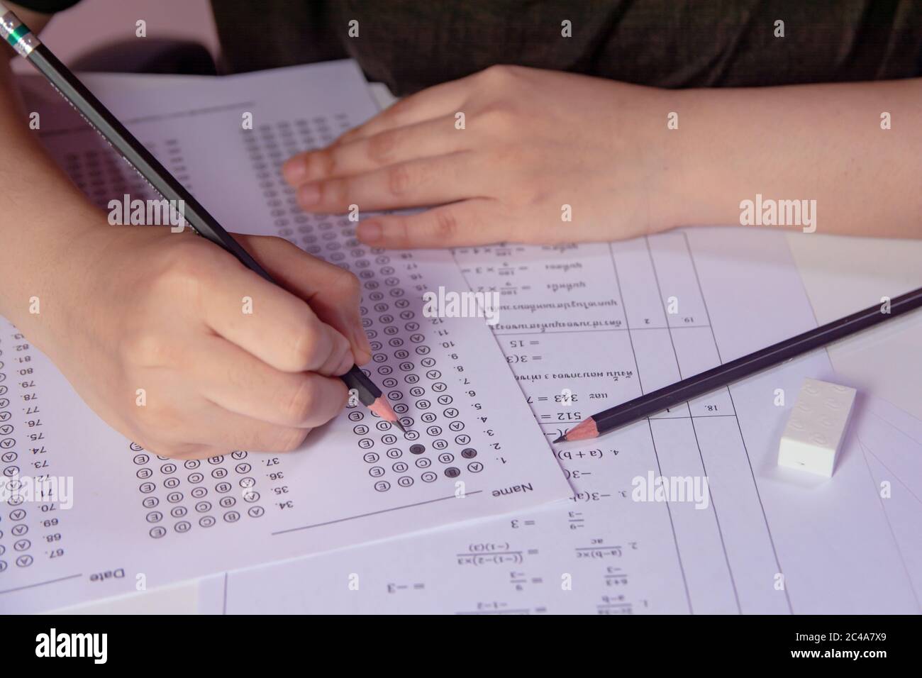 Students hand holding pencil writing selected choice on answer sheets ...