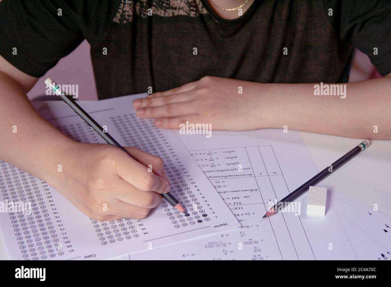 Students hand holding pencil writing selected choice on answer sheets ...