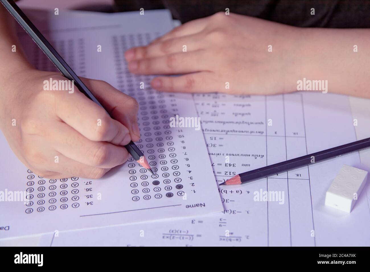 Students hand holding pencil writing selected choice on answer sheets ...