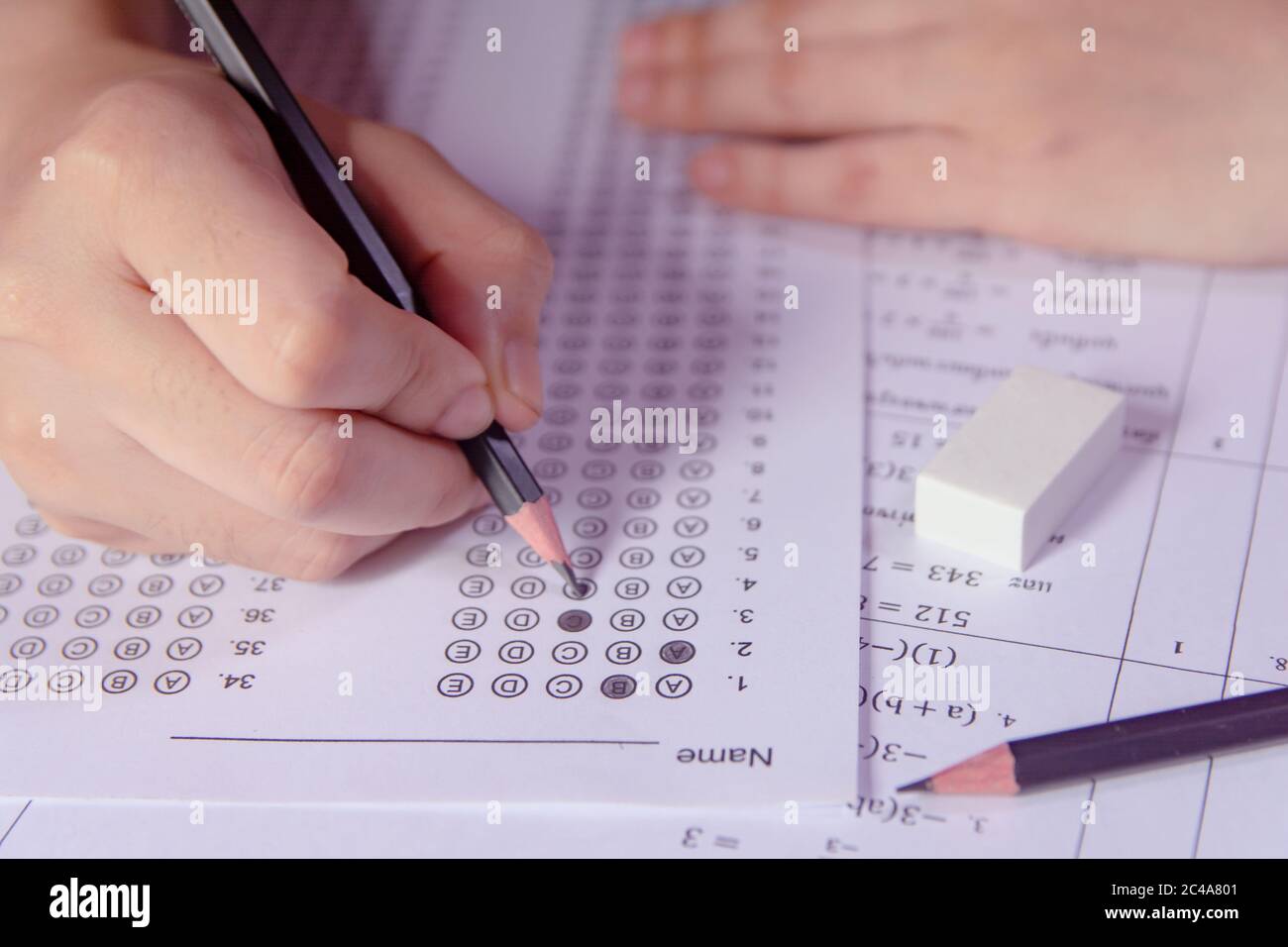 Students hand holding pencil writing selected choice on answer sheets ...