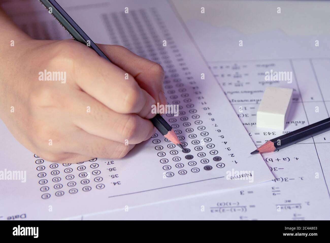 Students hand holding pencil writing selected choice on answer sheets ...