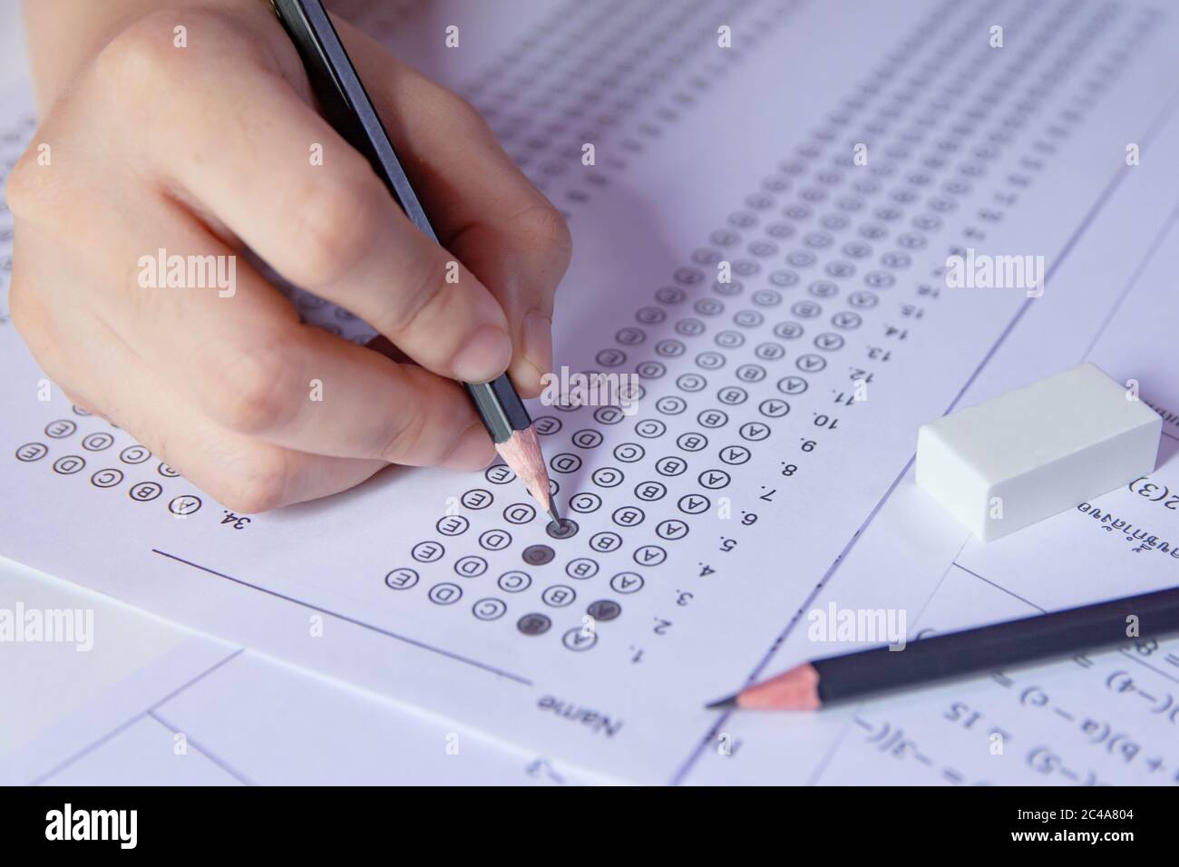 Students hand holding pencil writing selected choice on answer sheets ...