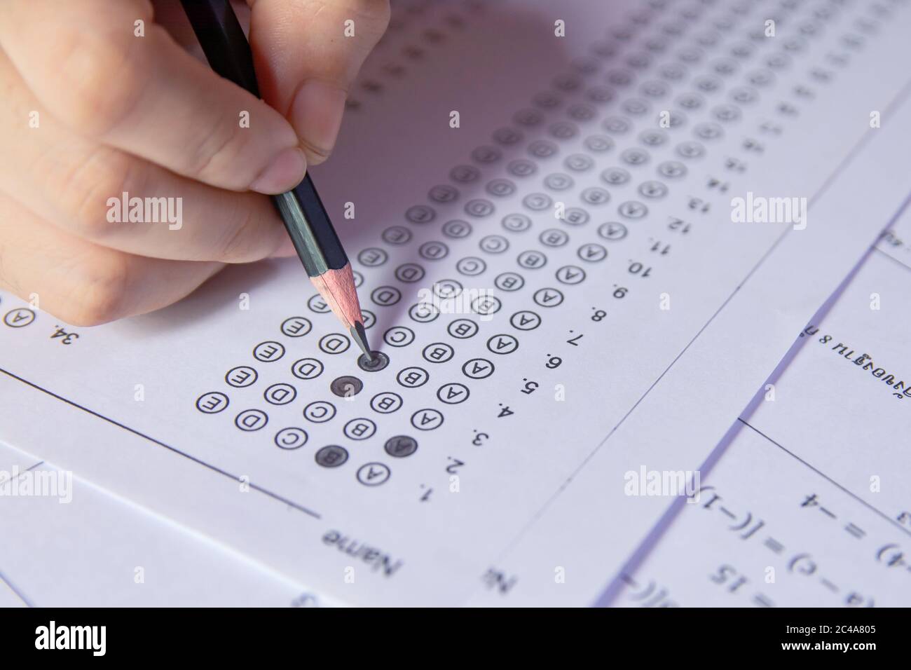 Students hand holding pencil writing selected choice on answer sheets ...