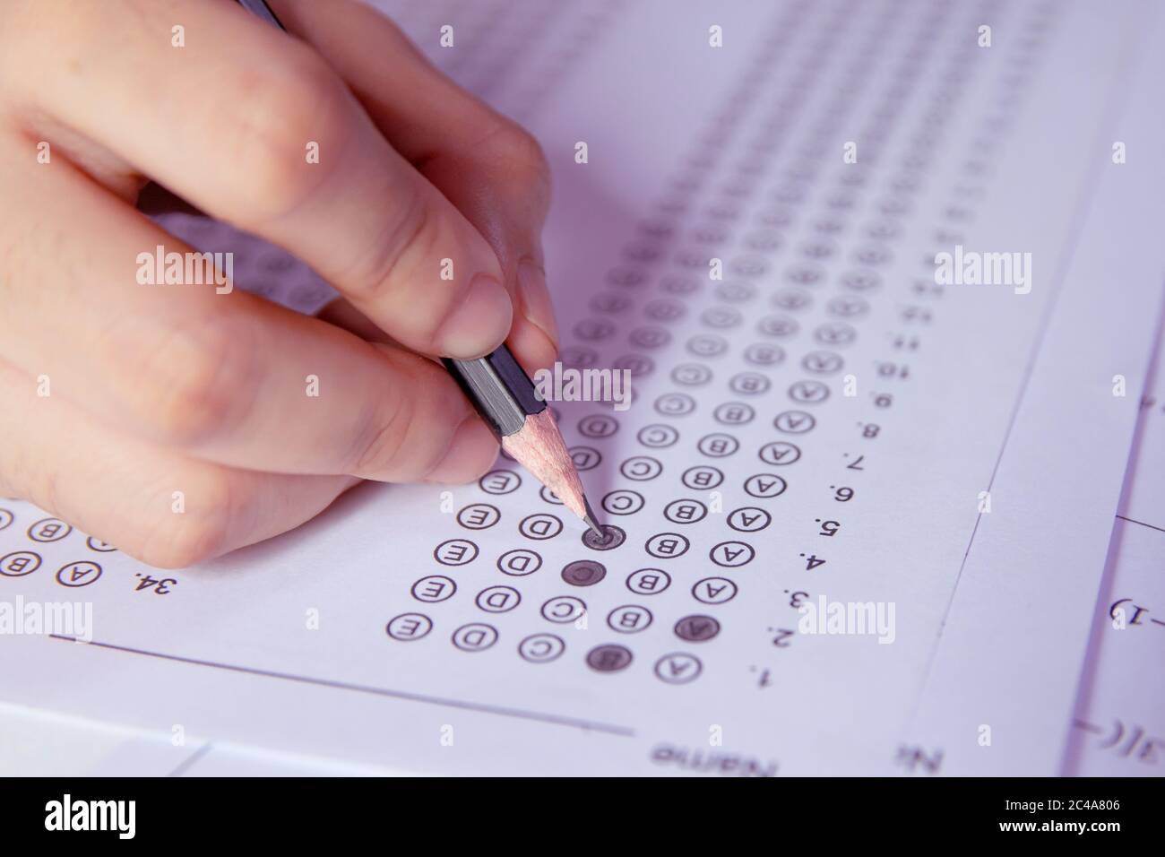 Students hand holding pencil writing selected choice on answer sheets ...