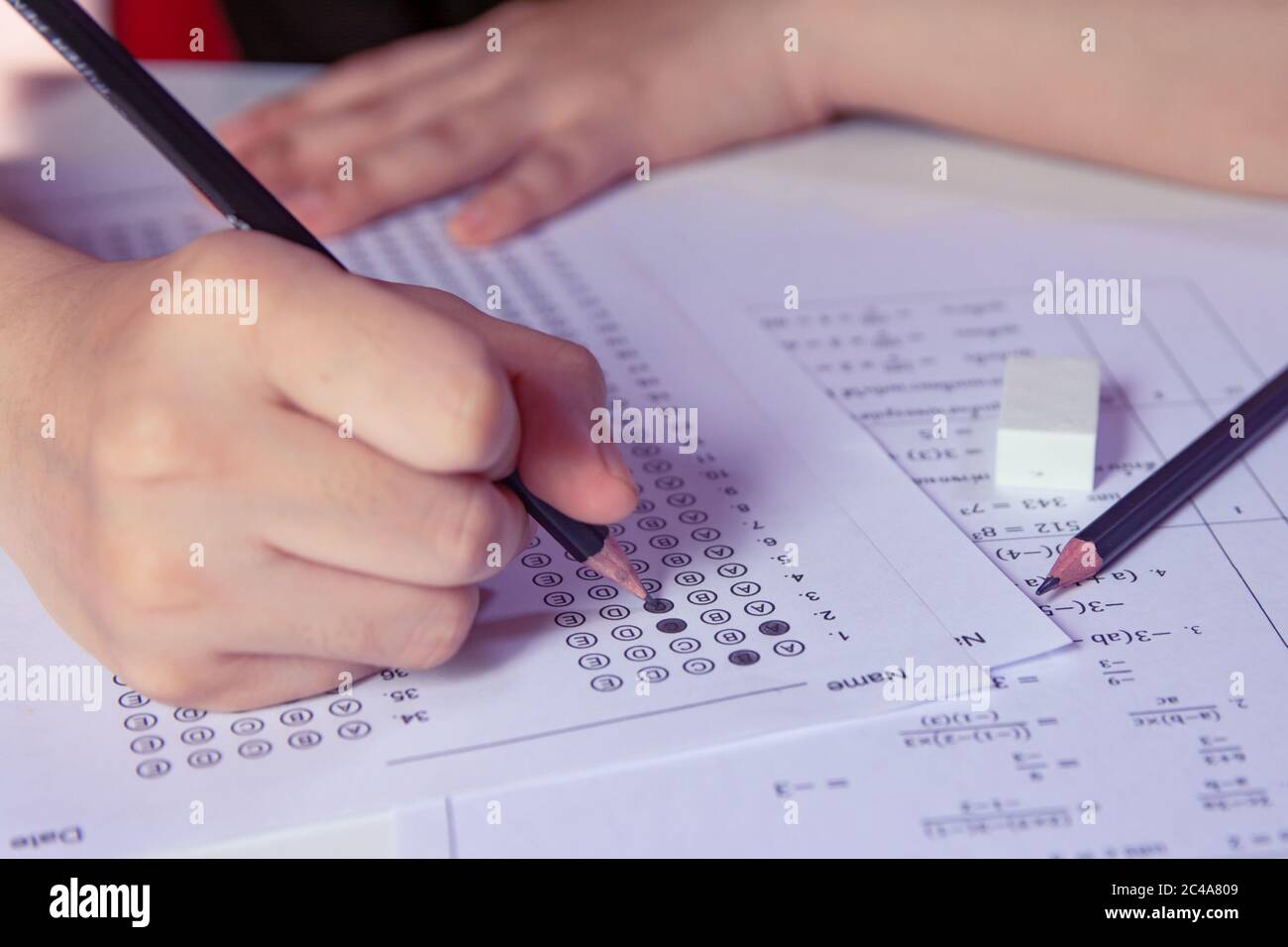Students hand holding pencil writing selected choice on answer sheets ...