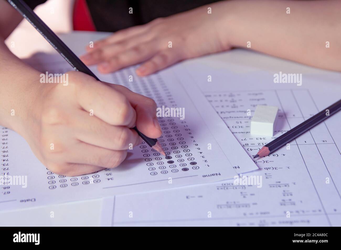 Students hand holding pencil writing selected choice on answer sheets ...