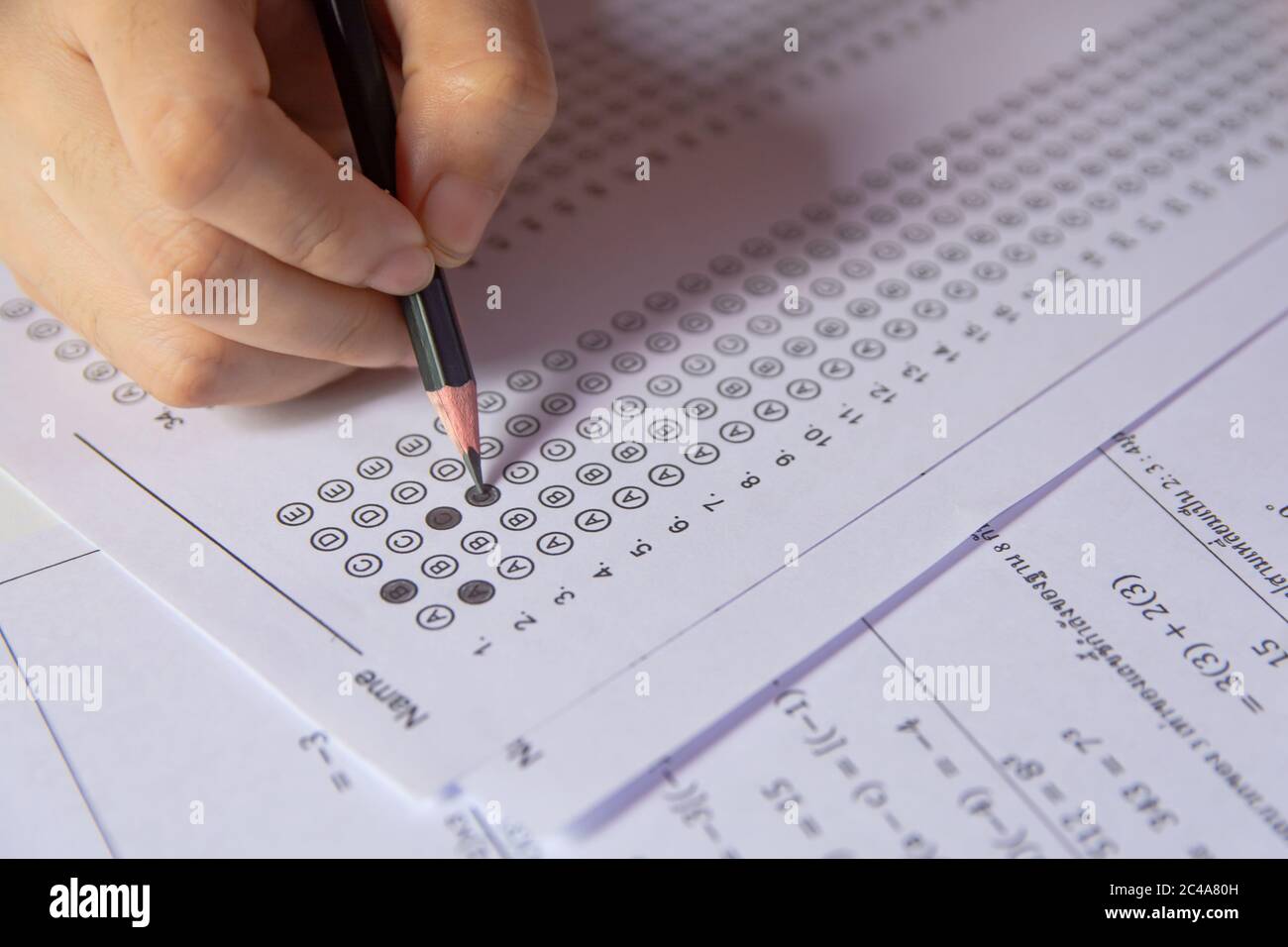 Students hand holding pencil writing selected choice on answer sheets ...