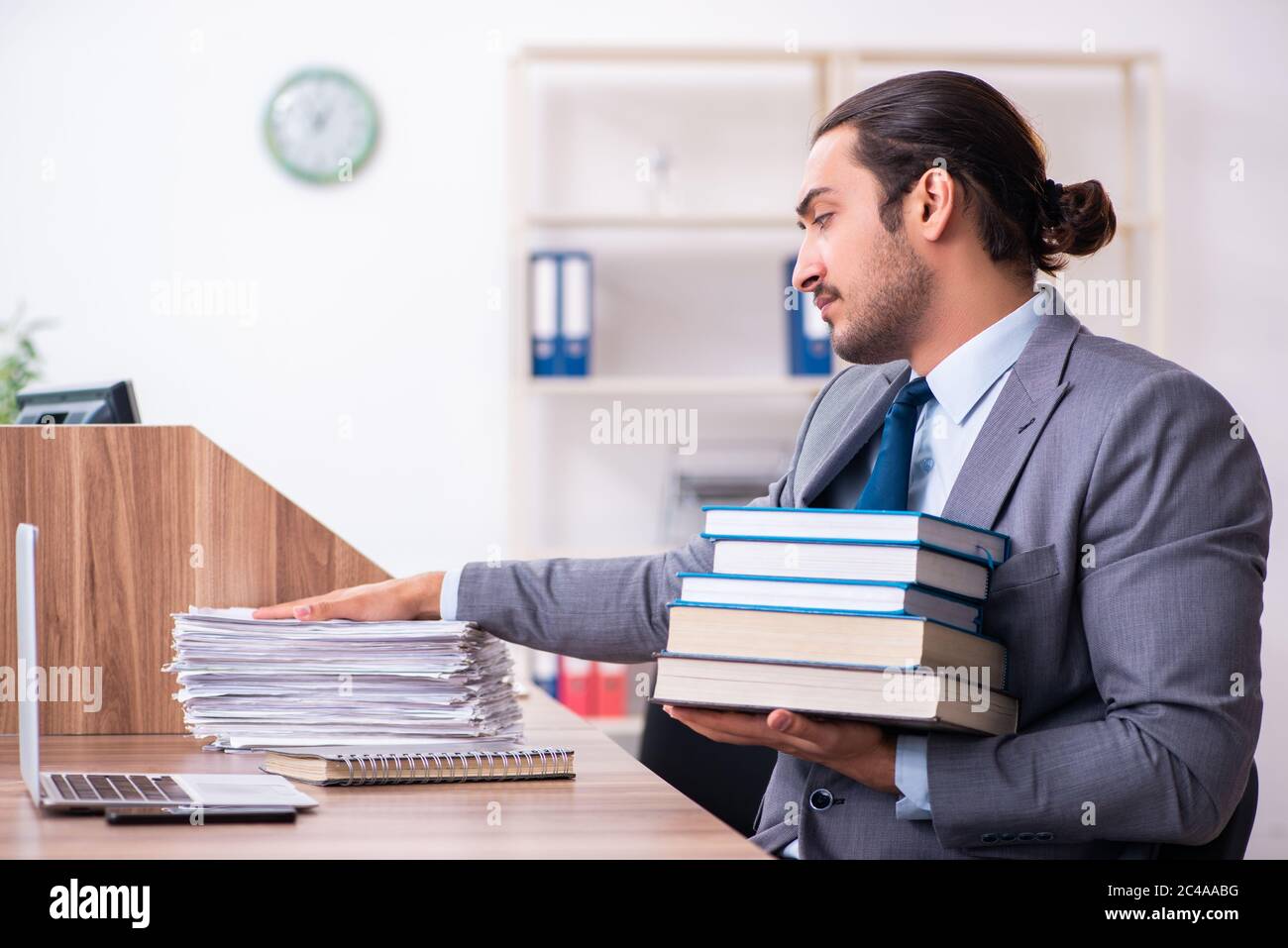 Young businessman reading books at workplace Stock Photo - Alamy