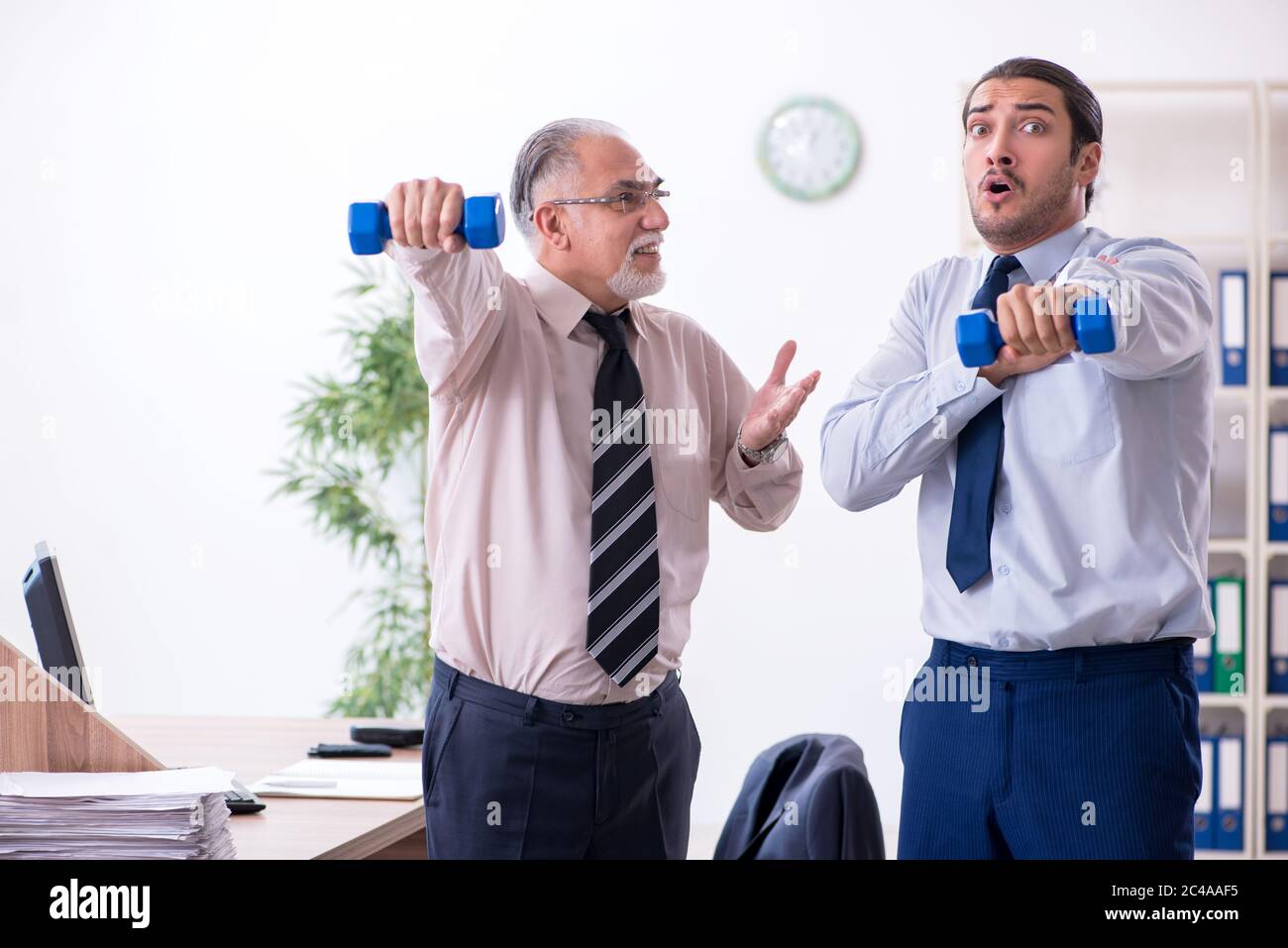 Two employees doing physical exercises at the workplace Stock Photo - Alamy