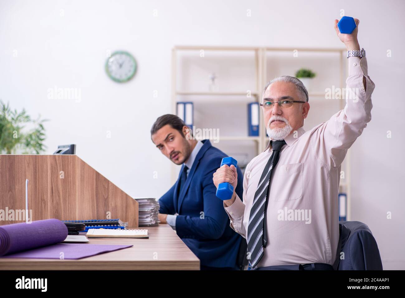 Two employees doing physical exercises at the workplace Stock Photo - Alamy
