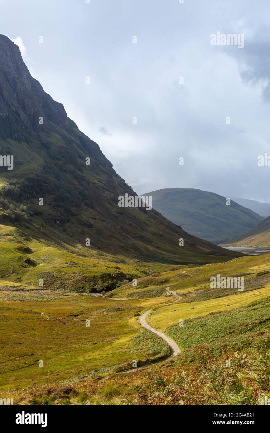 A pathway in a Scottish Highlands valley with mountains surrounding ...
